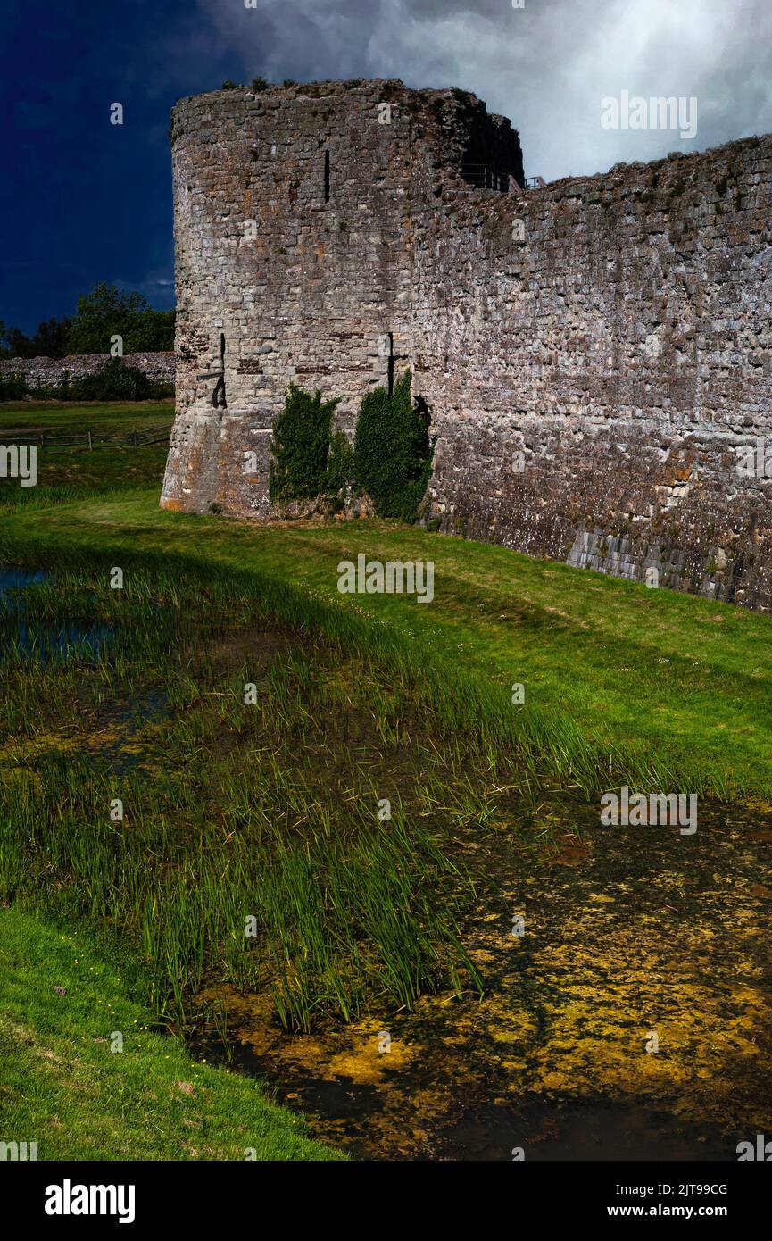 A deep moat fed by a spring and filled with water plants curves around ...