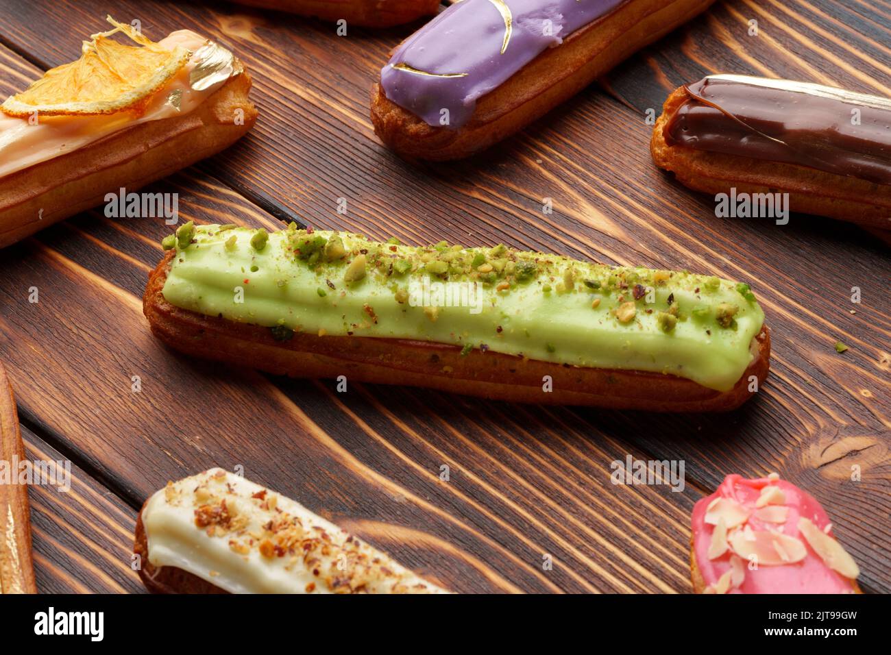 Assortment of sweet and colorful eclairs on wooden background Stock ...