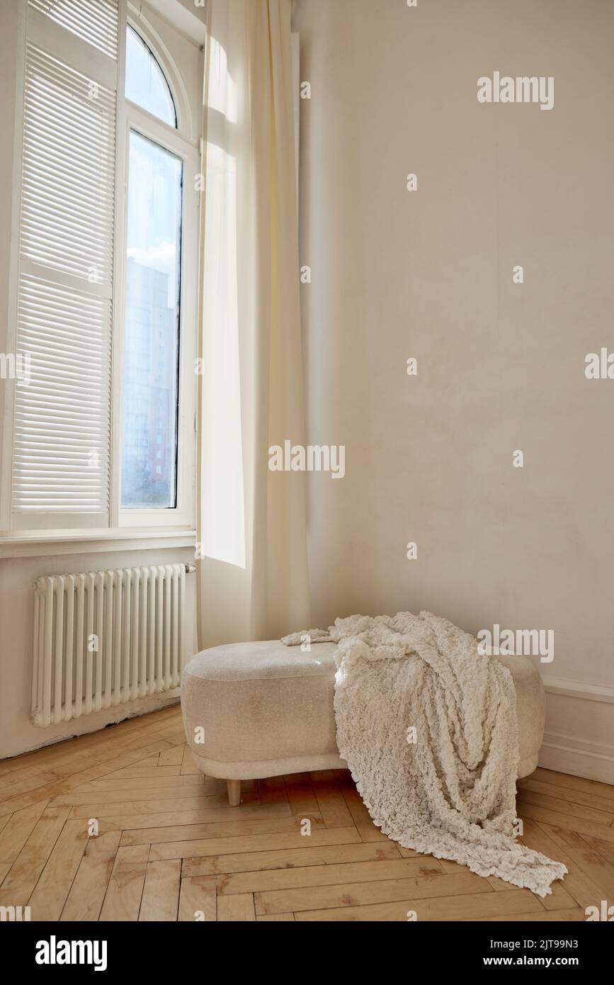 Ottoman with blanket near window in light room Stock Photo - Alamy