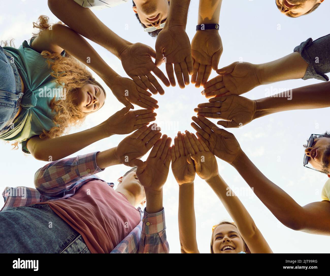 Multiracial team of happy young friends smiling and joining their hands together Stock Photo - Alamy