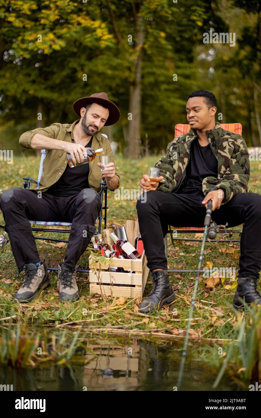 Two male friends fishing with alcoholic drinks Stock Photo - Alamy
