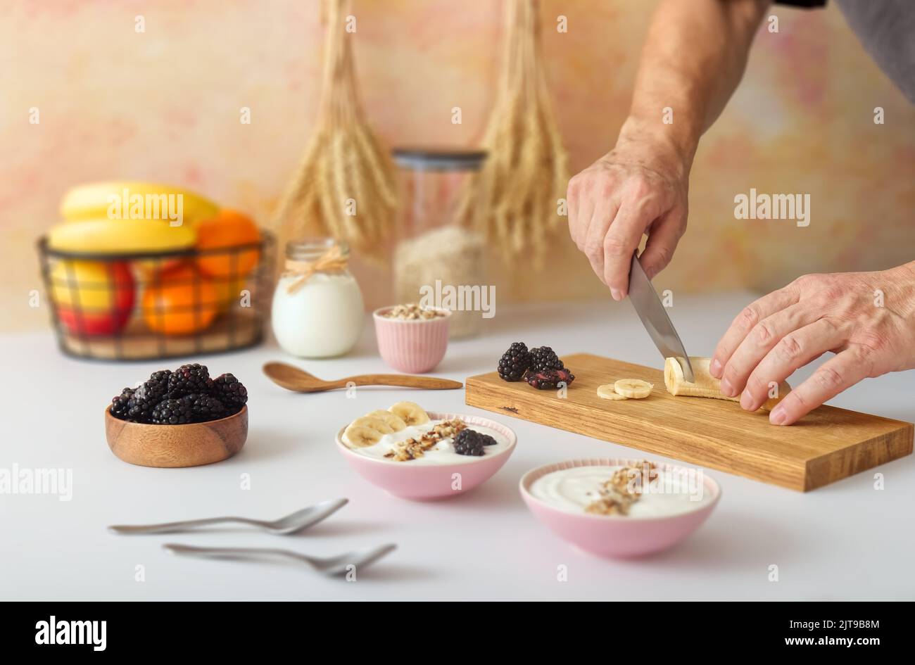 The chef prepares a healthy breakfast or snack. He slices a banana and ...
