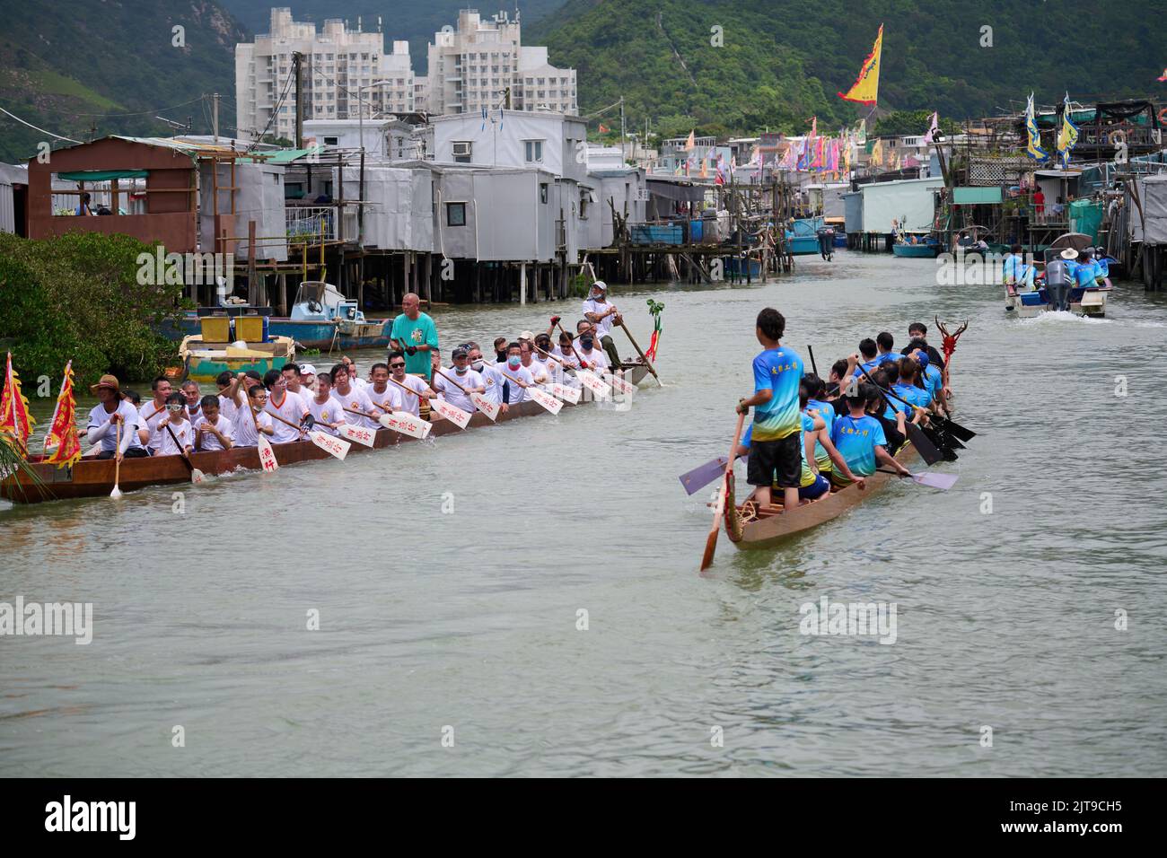 A vertical closeup of people riding on boats at the Dragon Boat ...