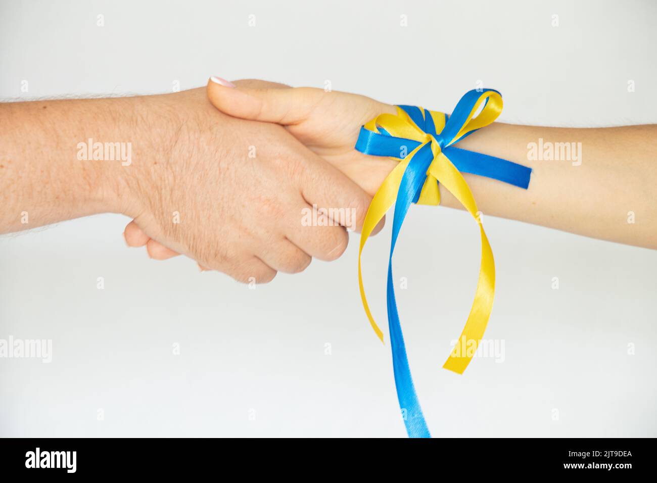 Handshake of a man and a woman with a ribbon on the hand of the flag of ...