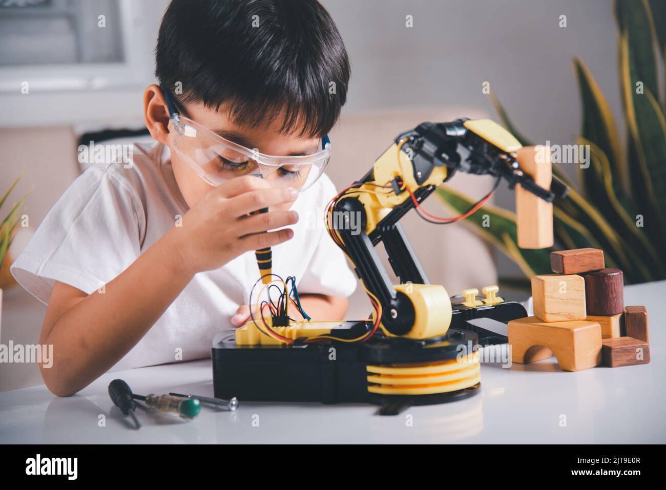 Happy Asian little kid boy using screwdriver to fixes screws robotic ...