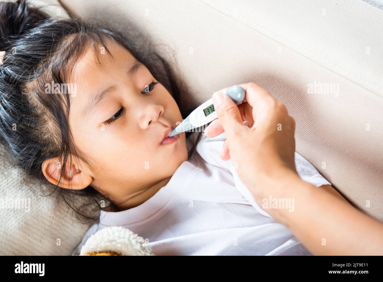 Sick kid. Mother checking temperature of her sick daughter with thermometer in mouth, child ...
