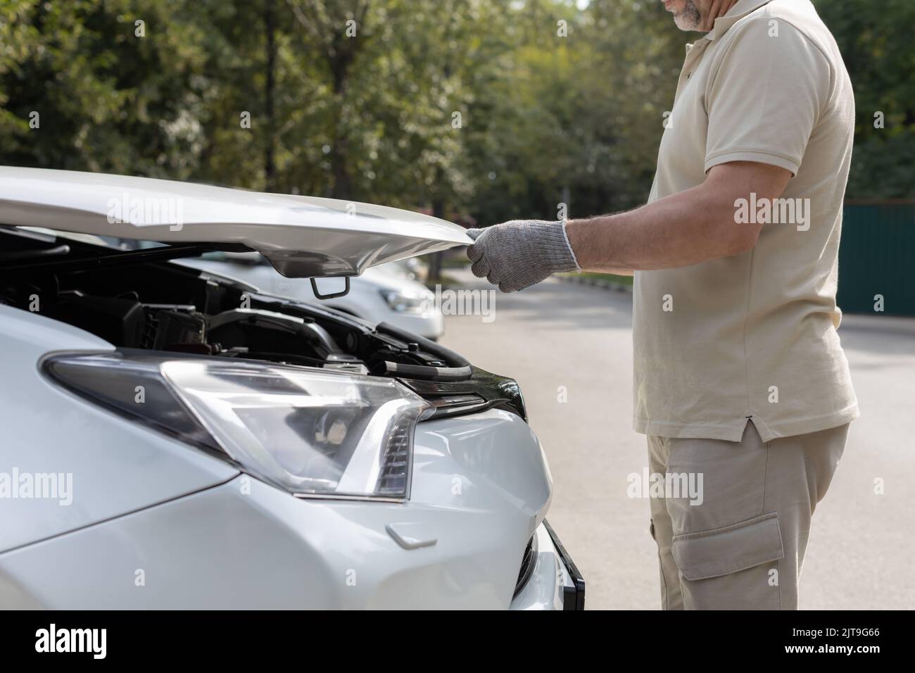 man opens the hood of a white car. Hand opens the hood to access the ...