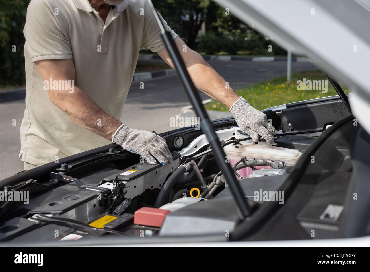 man opens cap of expansion tank in car. hand opens the lid of the water ...