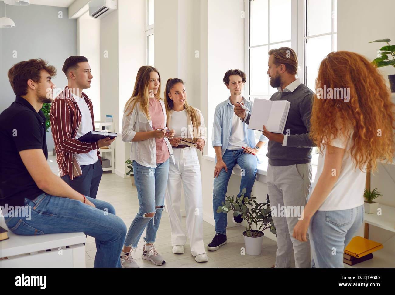 Group of students listening a professor explaining something and ...