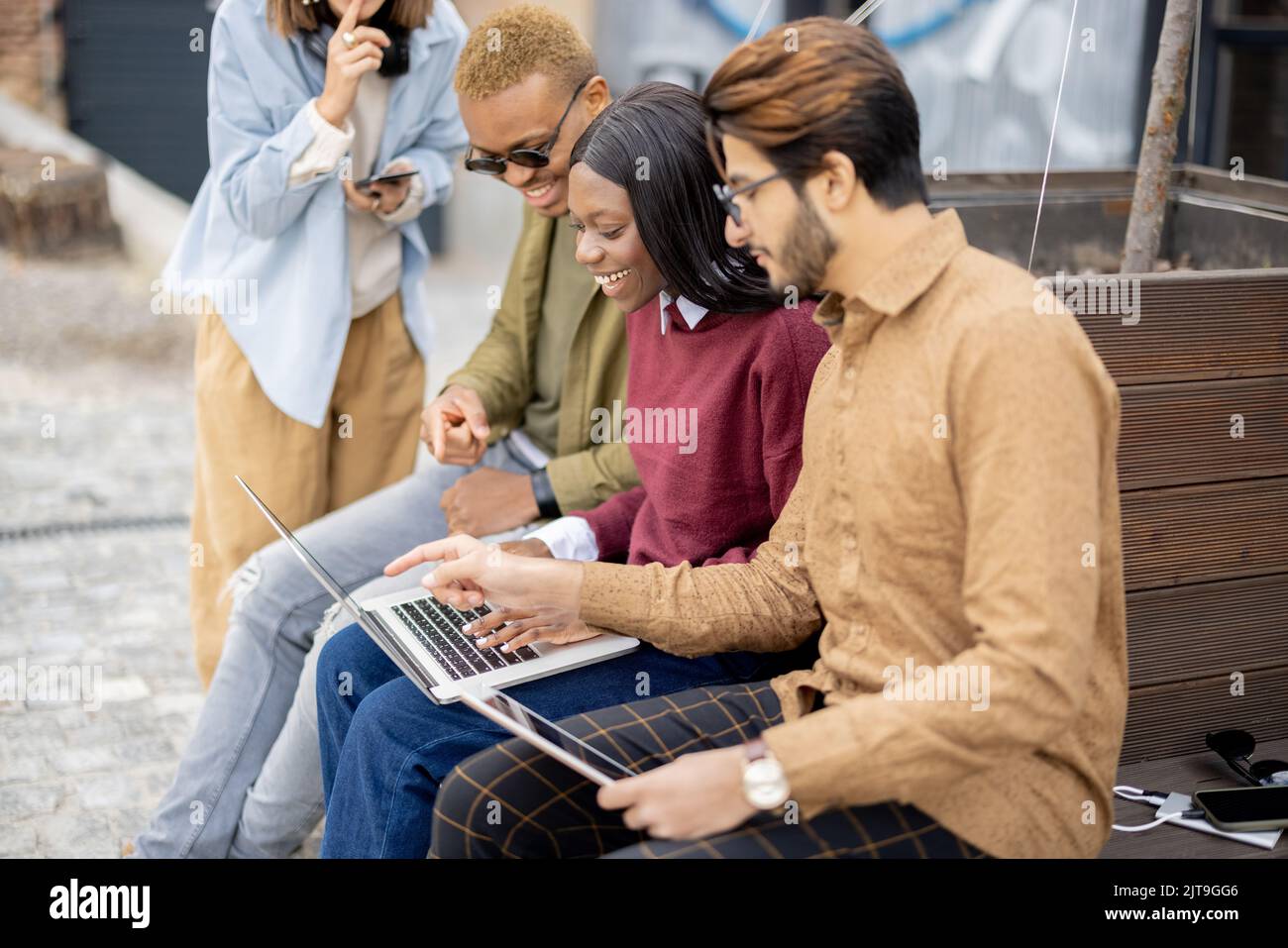 Multiracial students watch some on laptop outdoors Stock Photo - Alamy