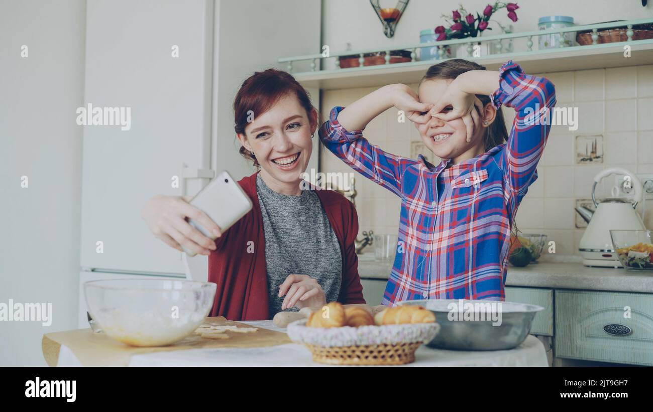 Smiling mother together with funny cute daughter taking selfie photo ...