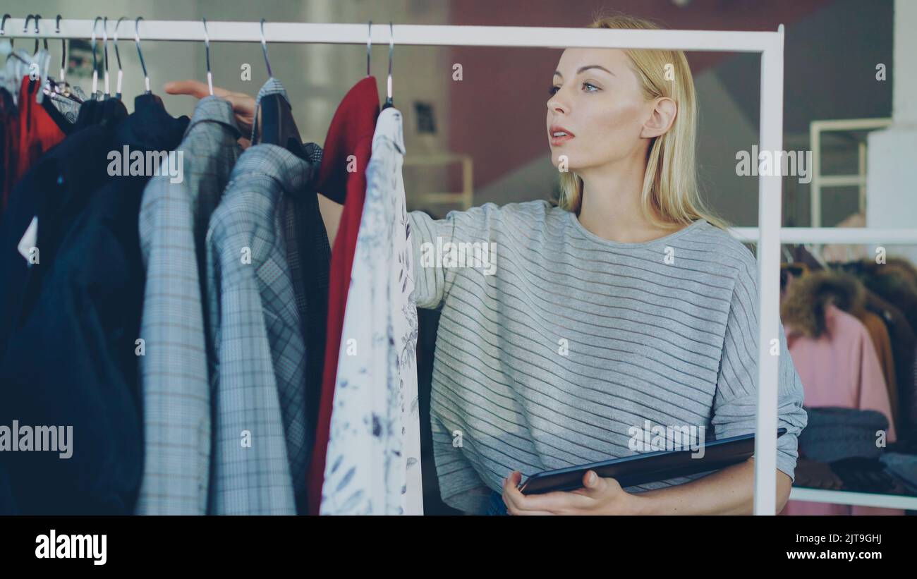 Young owner of clothing store is checking and counting garments on ...