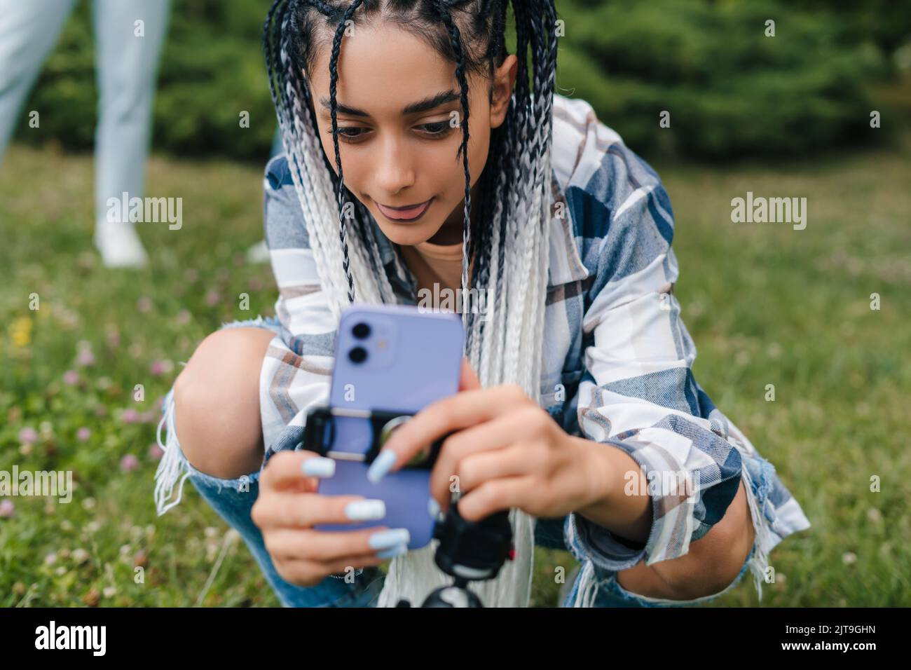 Girl with afro pigtails fixing phone on tripod to record video blog ...
