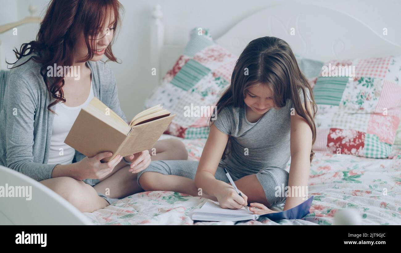 Careful mother helping her little cute daughter with homework for ...