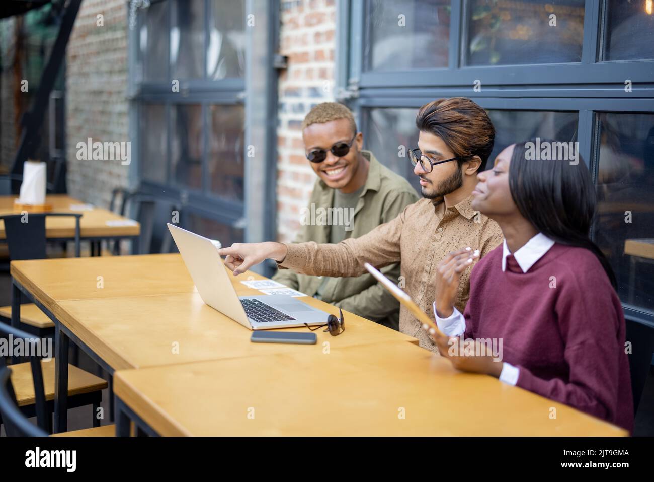 Multiracial students watch some on laptop outdoors Stock Photo - Alamy
