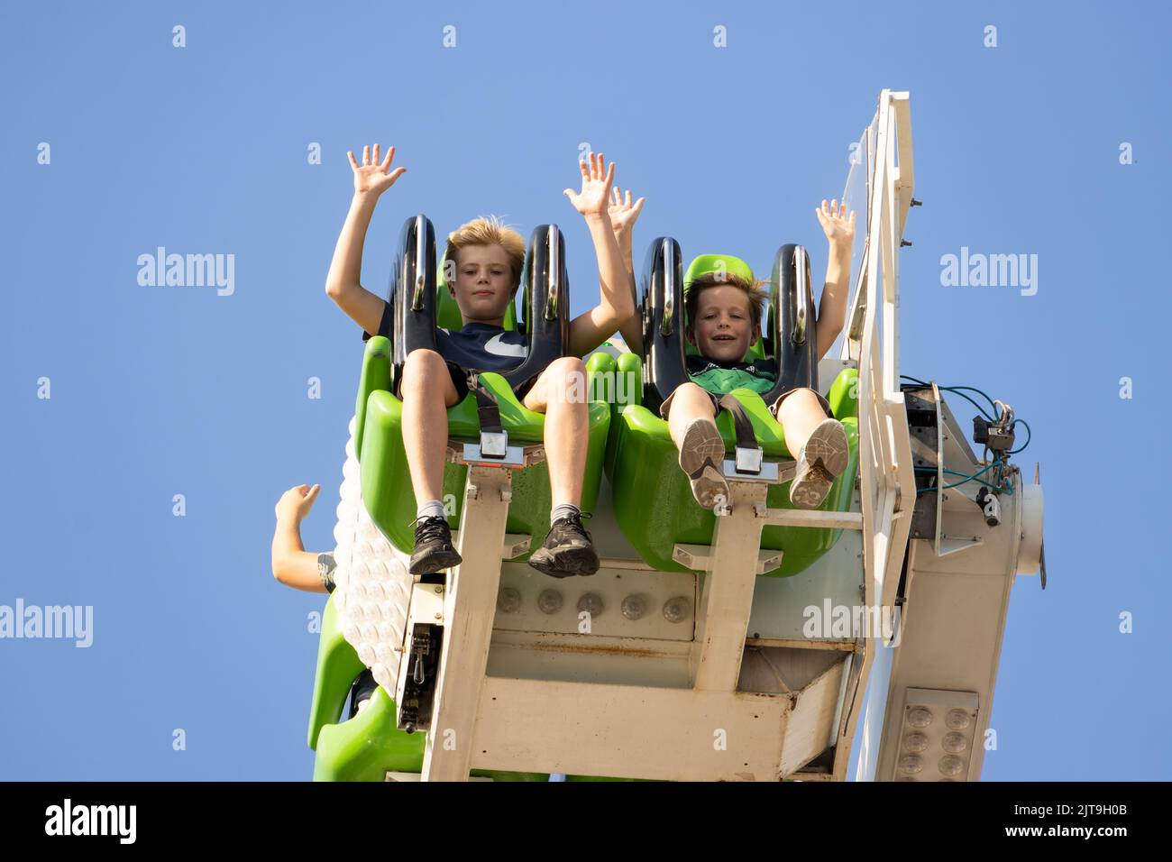 Two kids enjoying a "Booster" amusement ride (type pendulum) with their ...