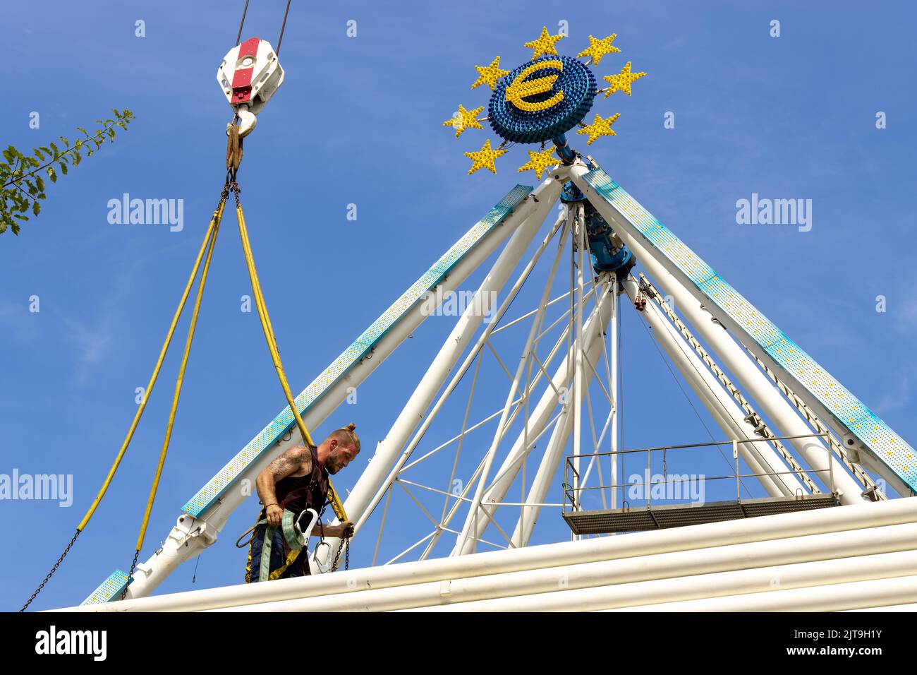 A worker is connecting cables to a part of a ferris wheel (giant wheel ... A worker is connecting cables to a part of a ferris wheel (giant wheel ...