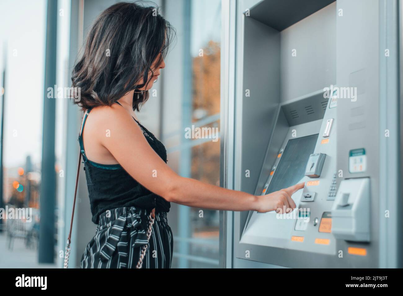 A Caucasian female model standing by an ATM Stock Photo - Alamy