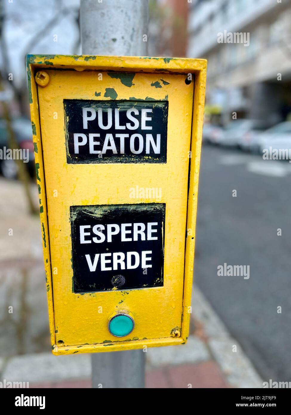 A yellow pedestrian crossing button in Madrid Translation-Push to cross ...