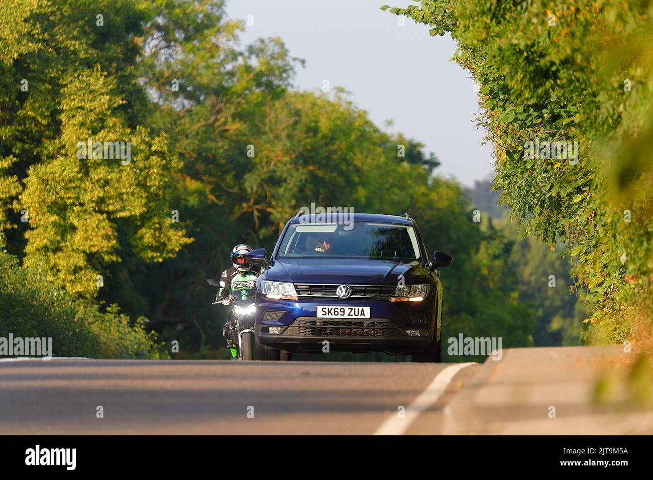 A motorcyclist hangs back behind a vehicle as they reach the brow of a ...