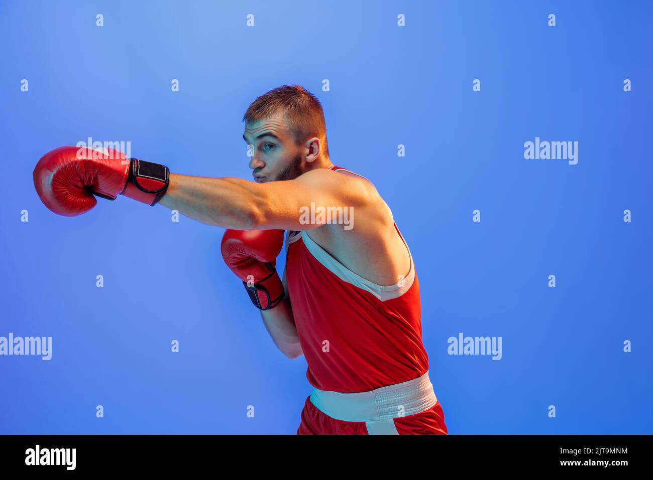 Right hook. Male boxer in red uniform and boxing gloves training ...