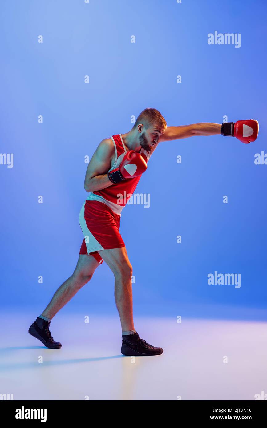 Right hook. Male boxer in red uniform and boxing gloves training ...