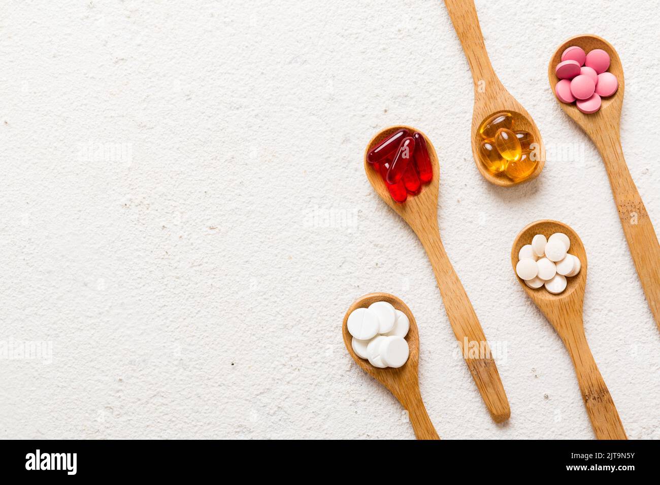 Vitamin capsules in a spoon on a colored background. Pills served as a ...