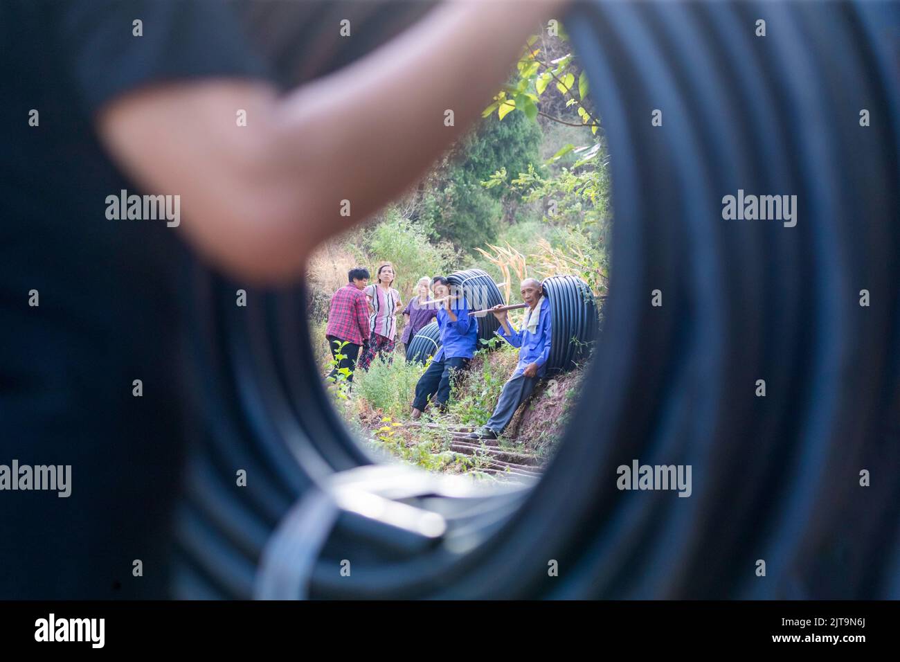 CHONGQING, CHINA - AUGUST 29, 2022 - Villagers carry water pipes up a ...
