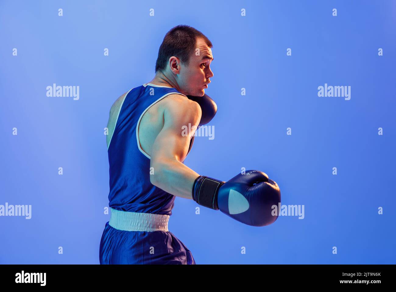 Practicing punch. Muscled man, male boxer in blue uniform and boxing ...