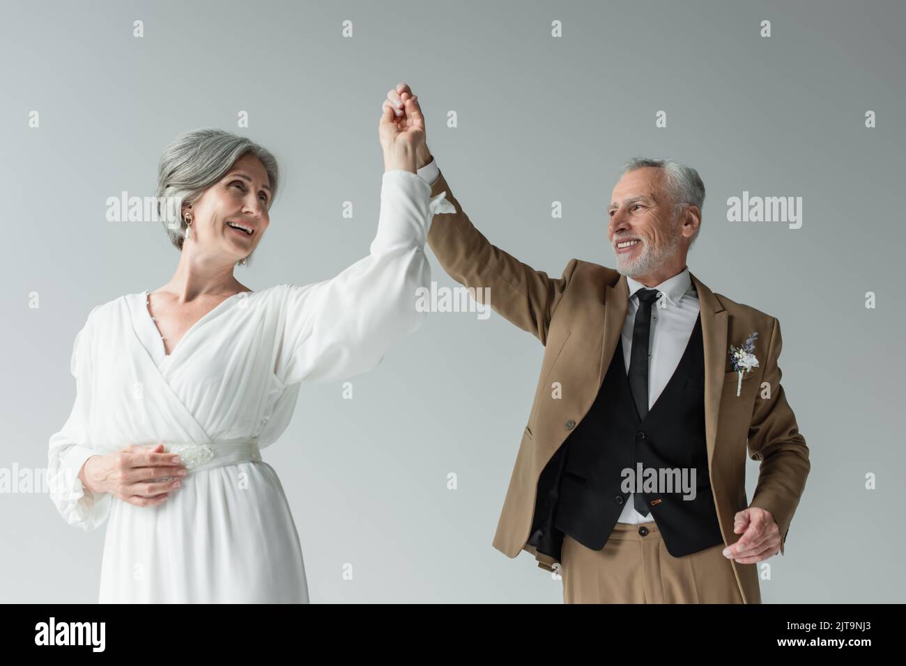 happy middle aged man in suit dancing with smiling bride in white ...