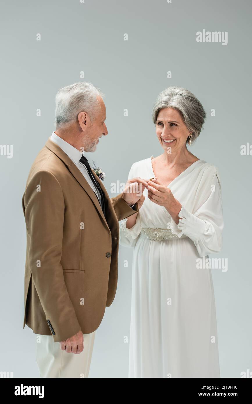 cheerful mature bride in white dress wearing golden engagement ring on ...