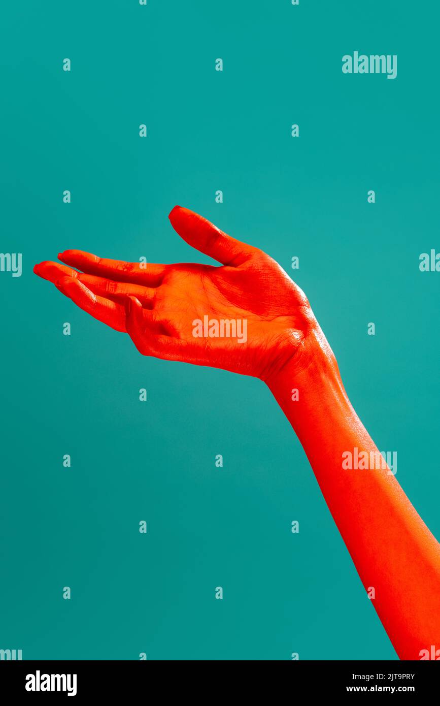 Authentic hands gesturing isolated on cyan color background in red neon ...