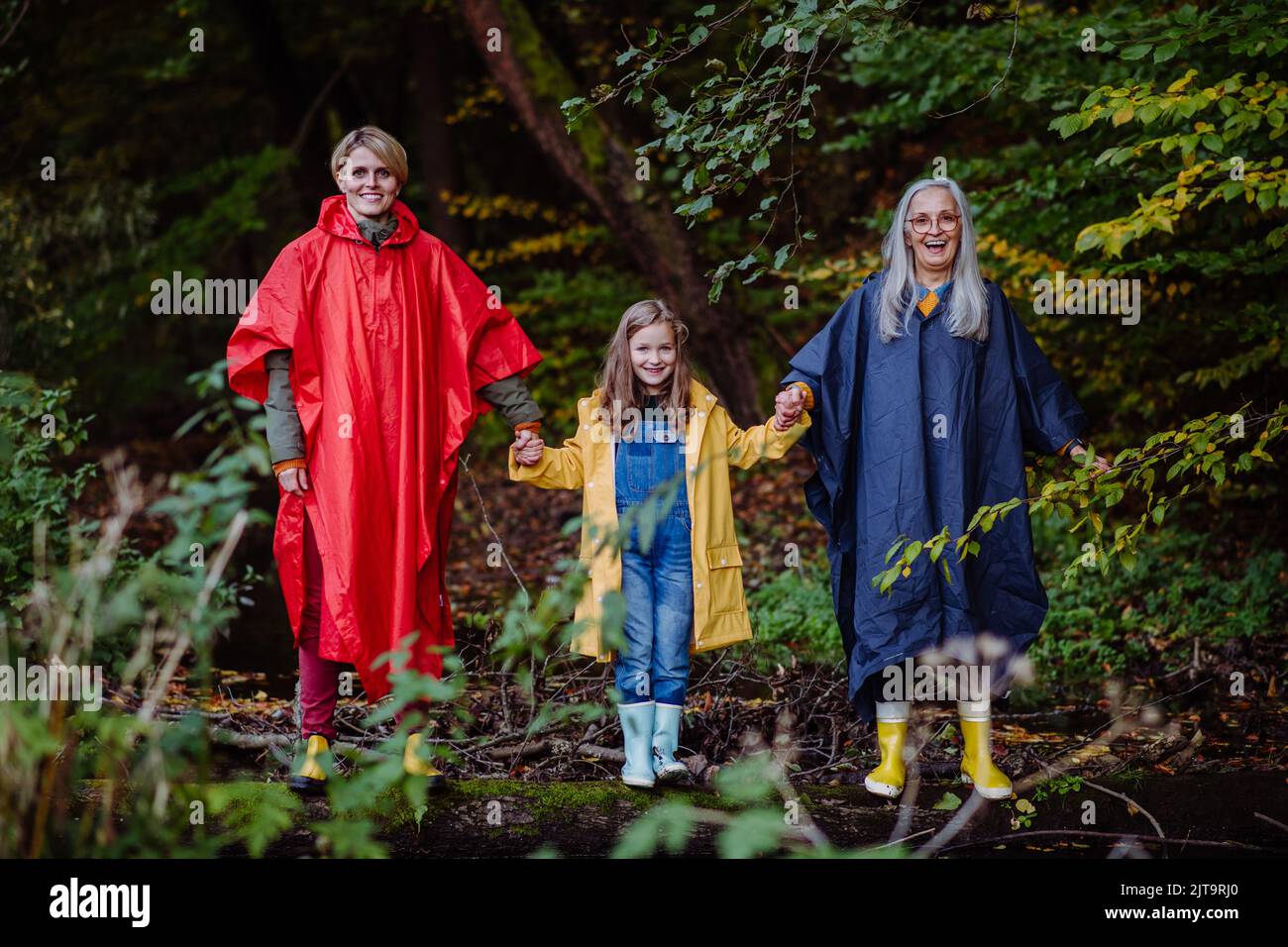 Portrait of small girl with mother and grandmother in raincoats ...