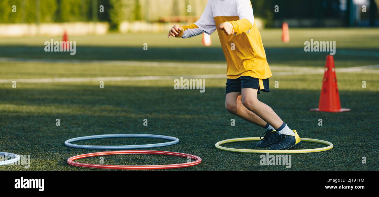 Little boy jumping over obstacles hula hoops on kids sports education ...