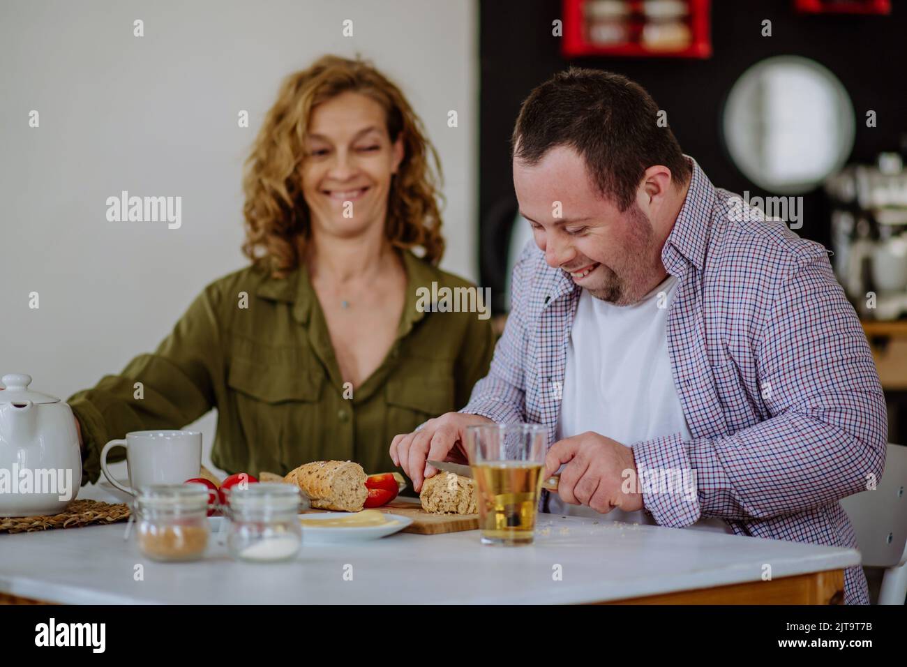 Portrait of happy young man with Down syndrome with his mother at home ...