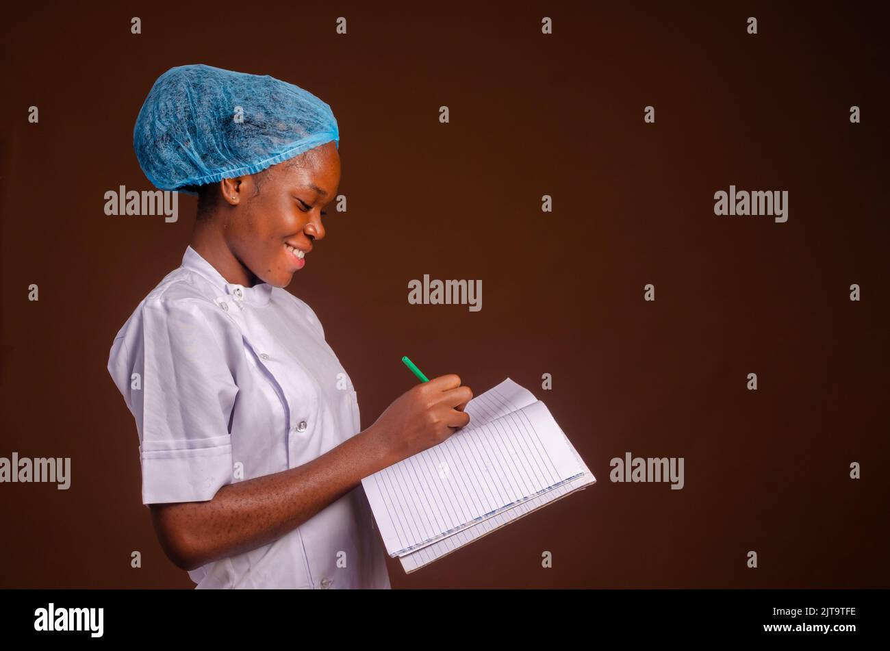Beautiful nurse smiling and taking notes Stock Photo - Alamy