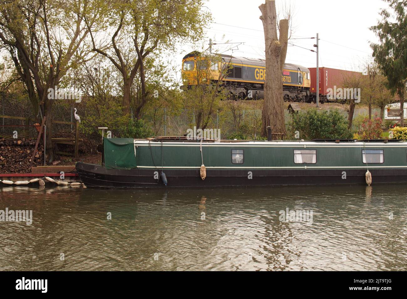 A long, low, green barge moored in the canal basin at Ely ...
