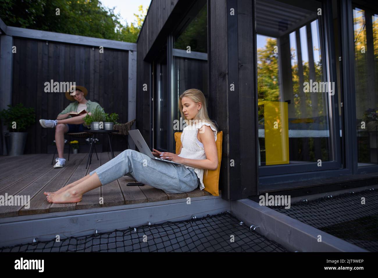 Happy young couple with laptop resting outdoors in a tiny house ...