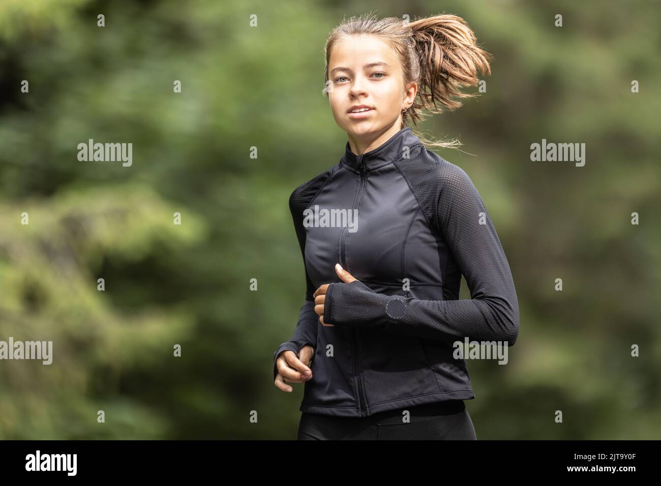 Young girl with a ponytail and black clothes is jogging outdoors Stock ...
