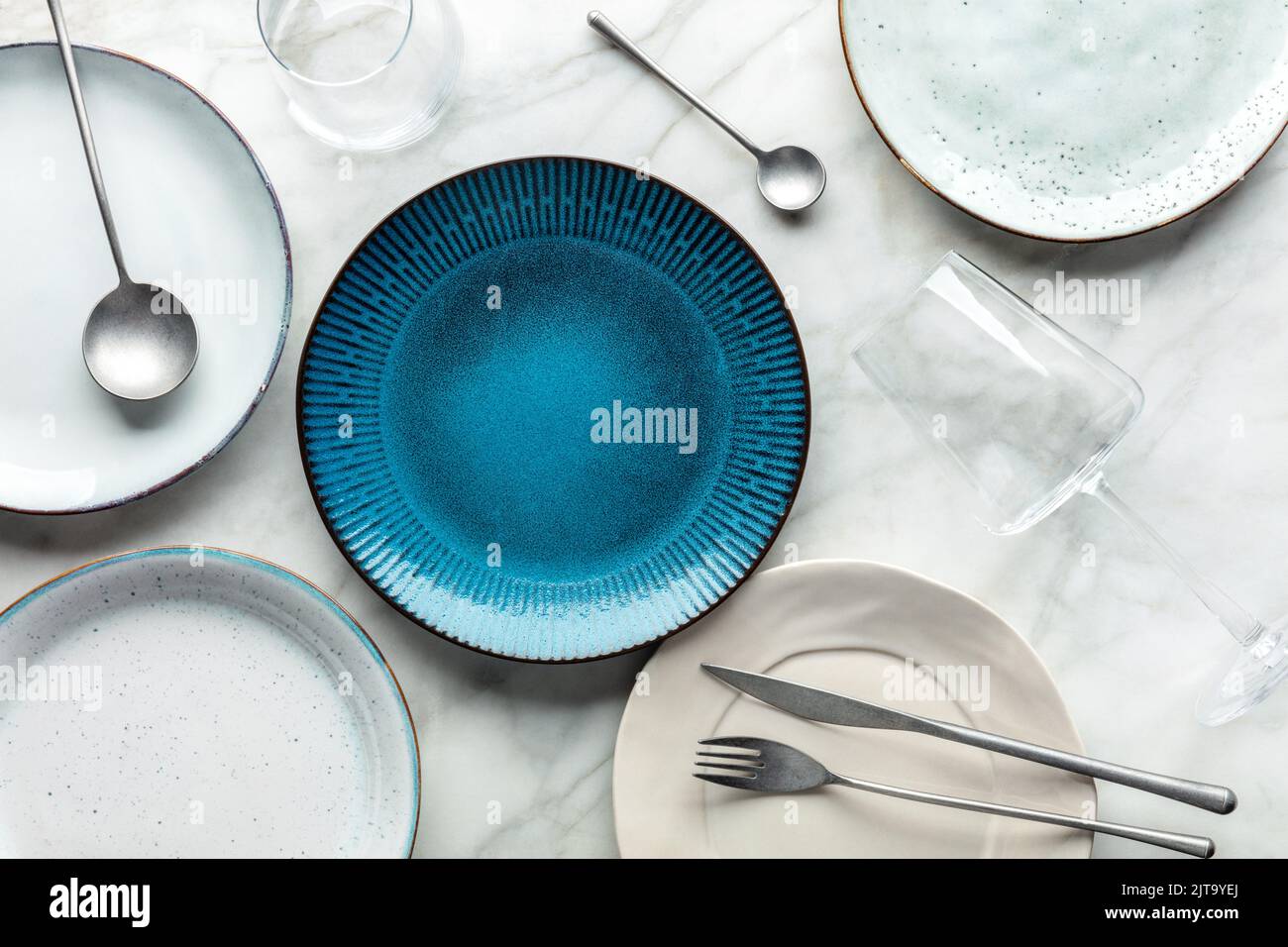 Modern tableware set with cutlery and a vibrant blue plate, with ...