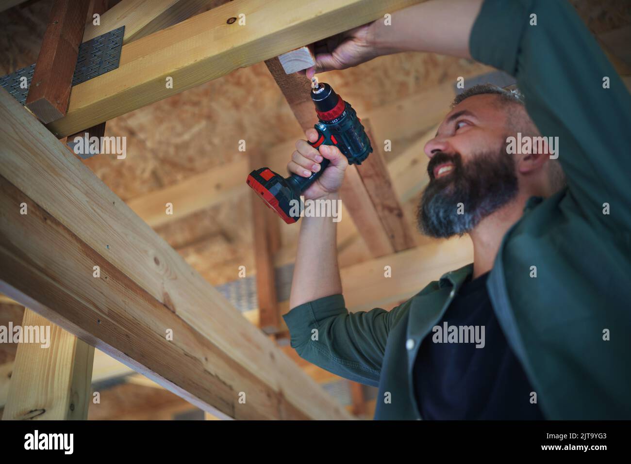 Construction worker working with screwdriver on wooden frame, diy eco ...