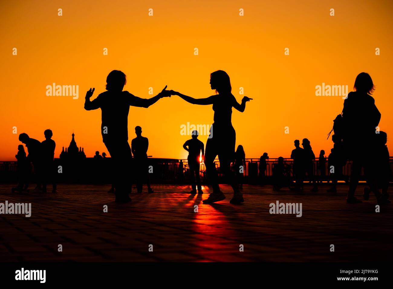 Woman and man couple silhouettes dancing against warm sunset orange sky ...