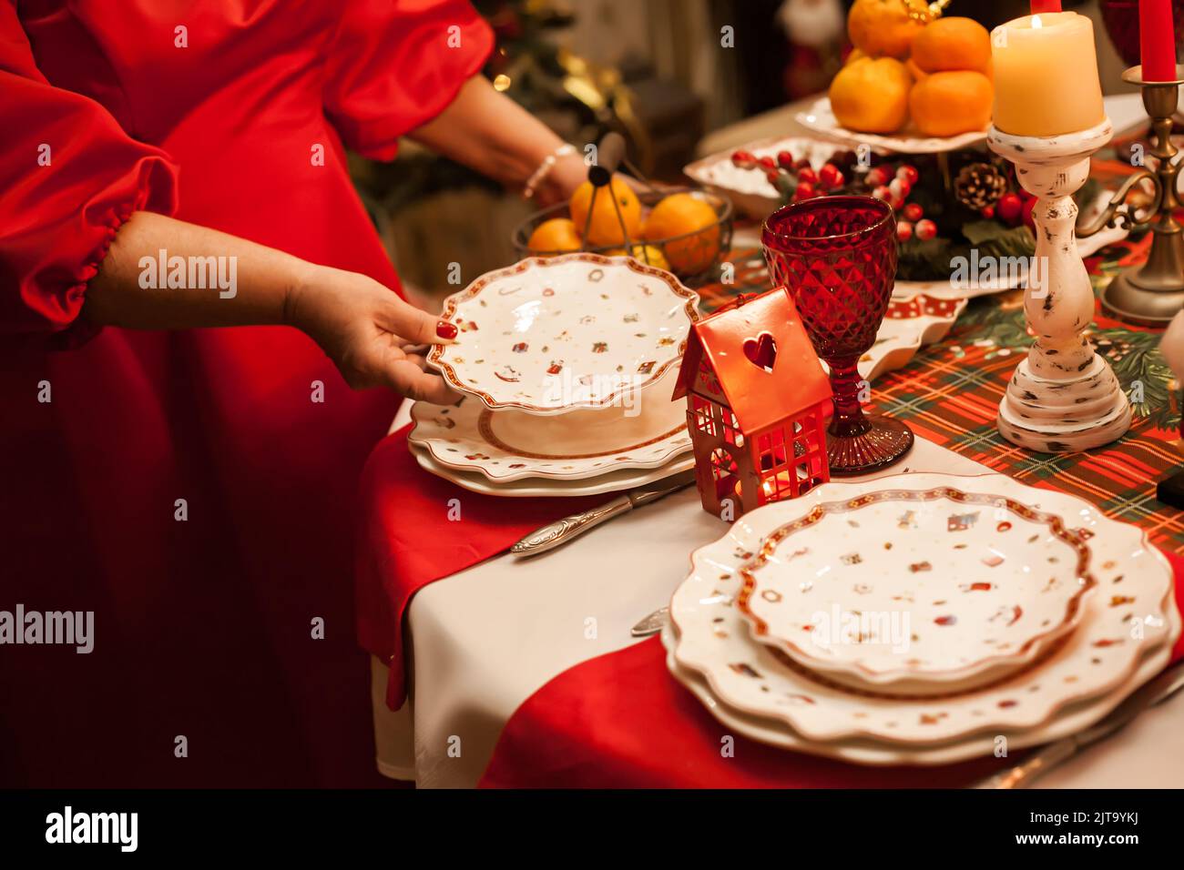 Christmas serving at home. An adult woman in a red dress makes a ...
