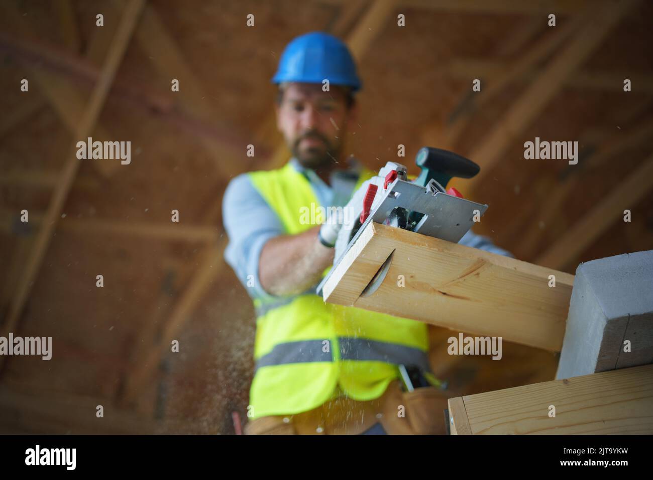 Low angle view of handyman working with circular saw on wooden ...