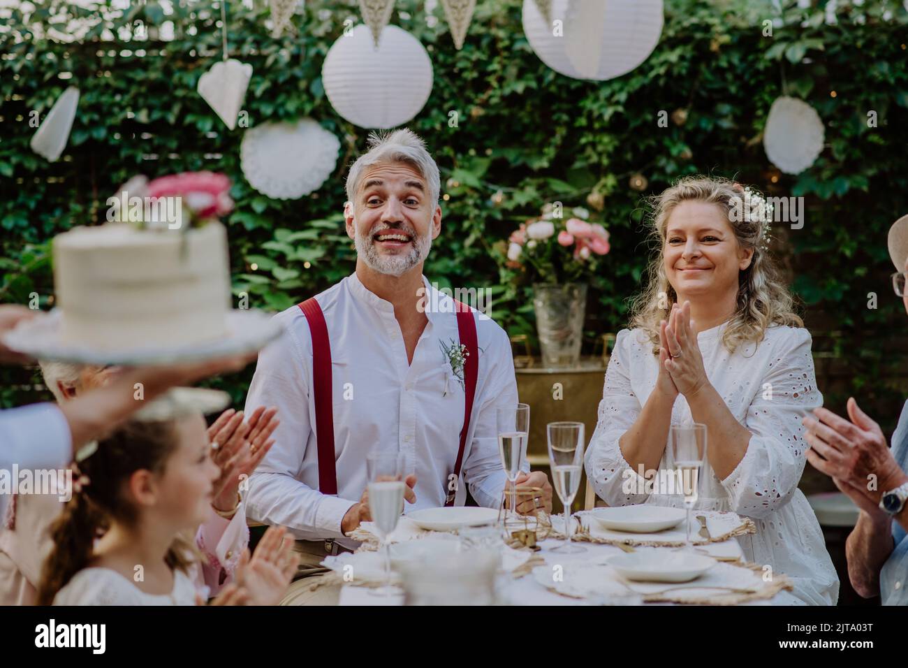 Mature bride and groom with guests at wedding reception outside in the ...