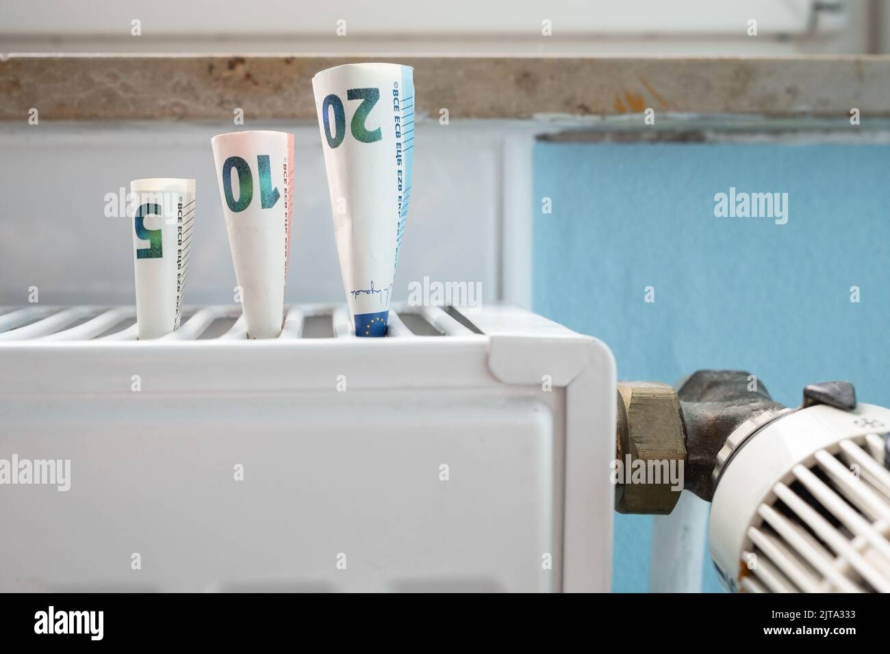 Euro banknotes in a radiator as a scale symbolizing the increase in gas ...