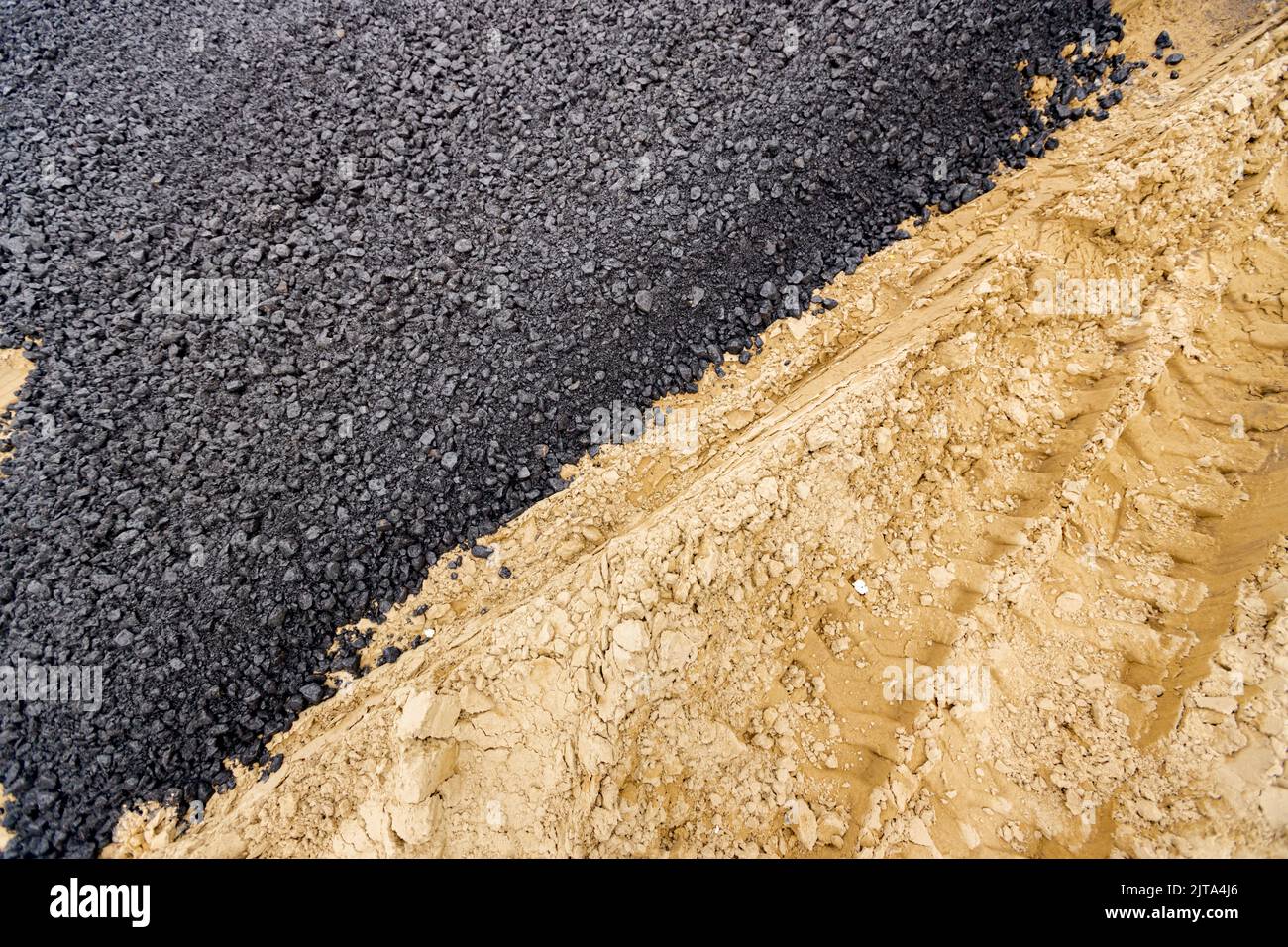 Machine emptied the hot and fresh asphalt into the sand in which are ...