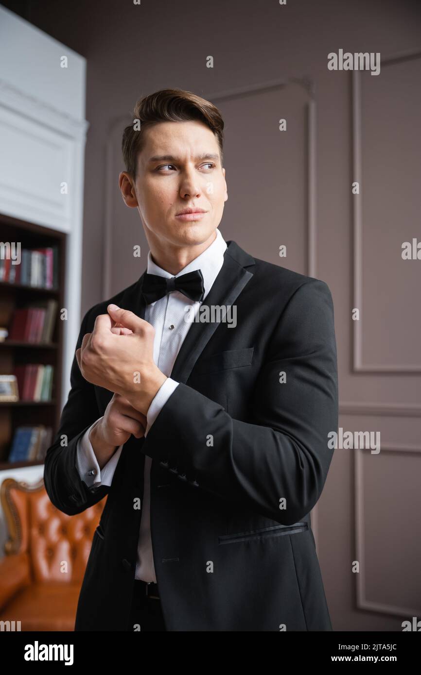 Man in formal wear adjusting sleeve of jacket at home Stock Photo - Alamy