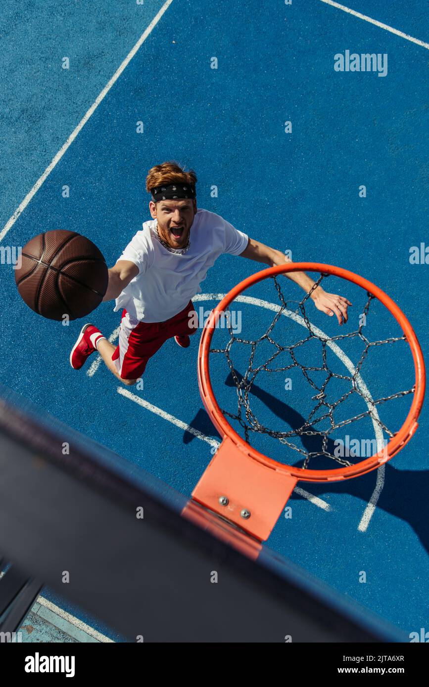 top view of redhead excited man throwing ball into basketball hoop ...