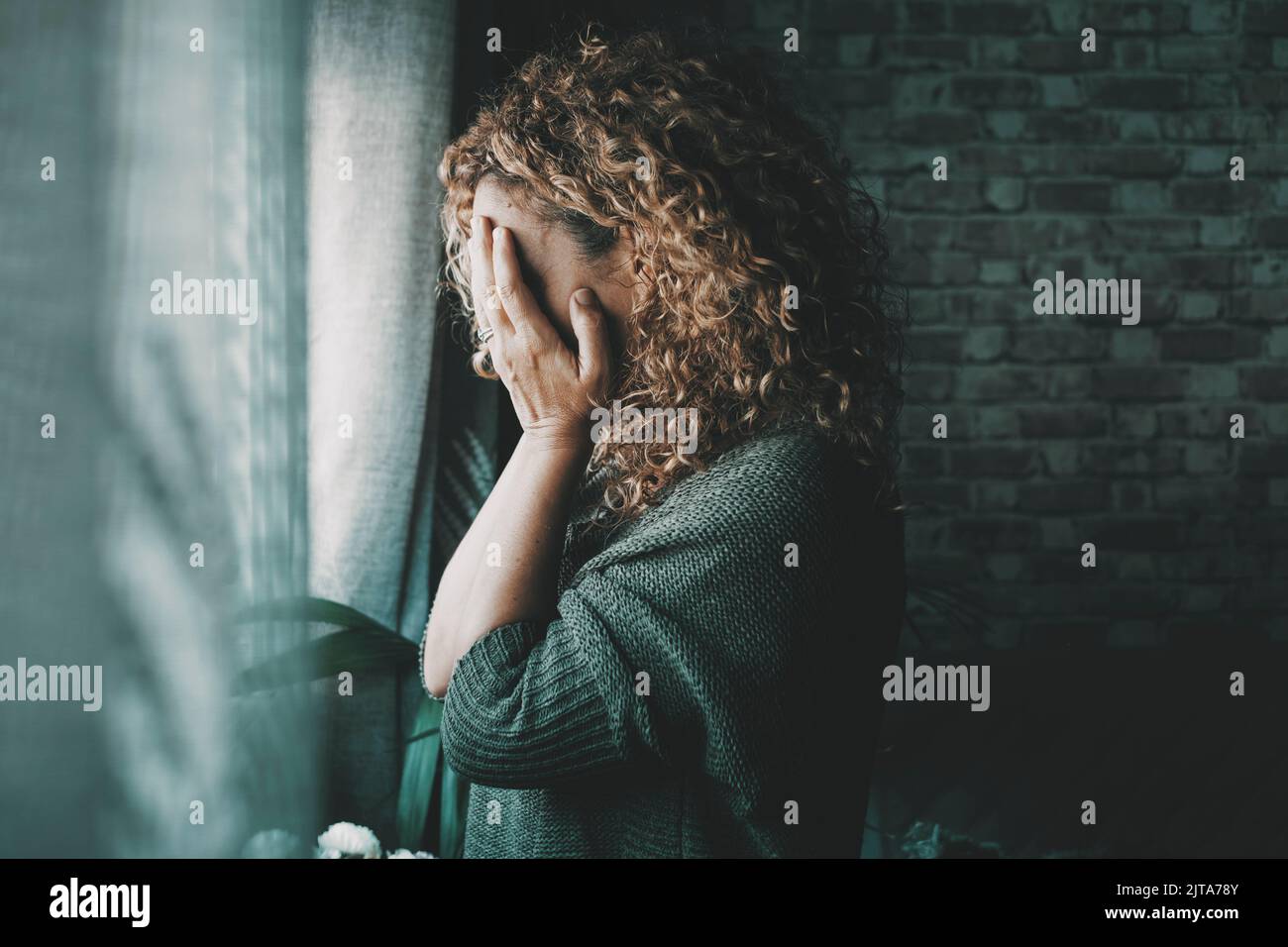 Sad and worried woman side portrait at home in the dark looking outside ...